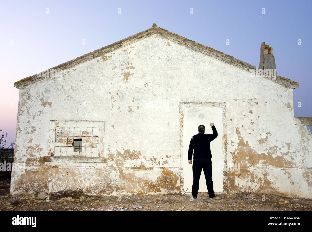 Man knocking on an abandoned house blocked off door at dusk. image ...