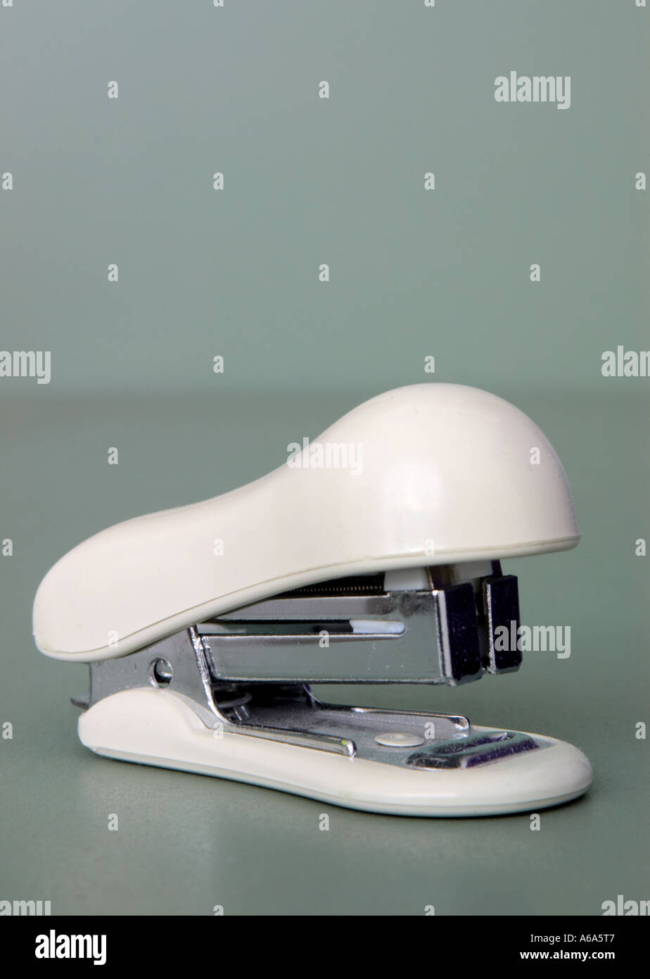 a small white stapler against a green background Stock Photo - Alamy