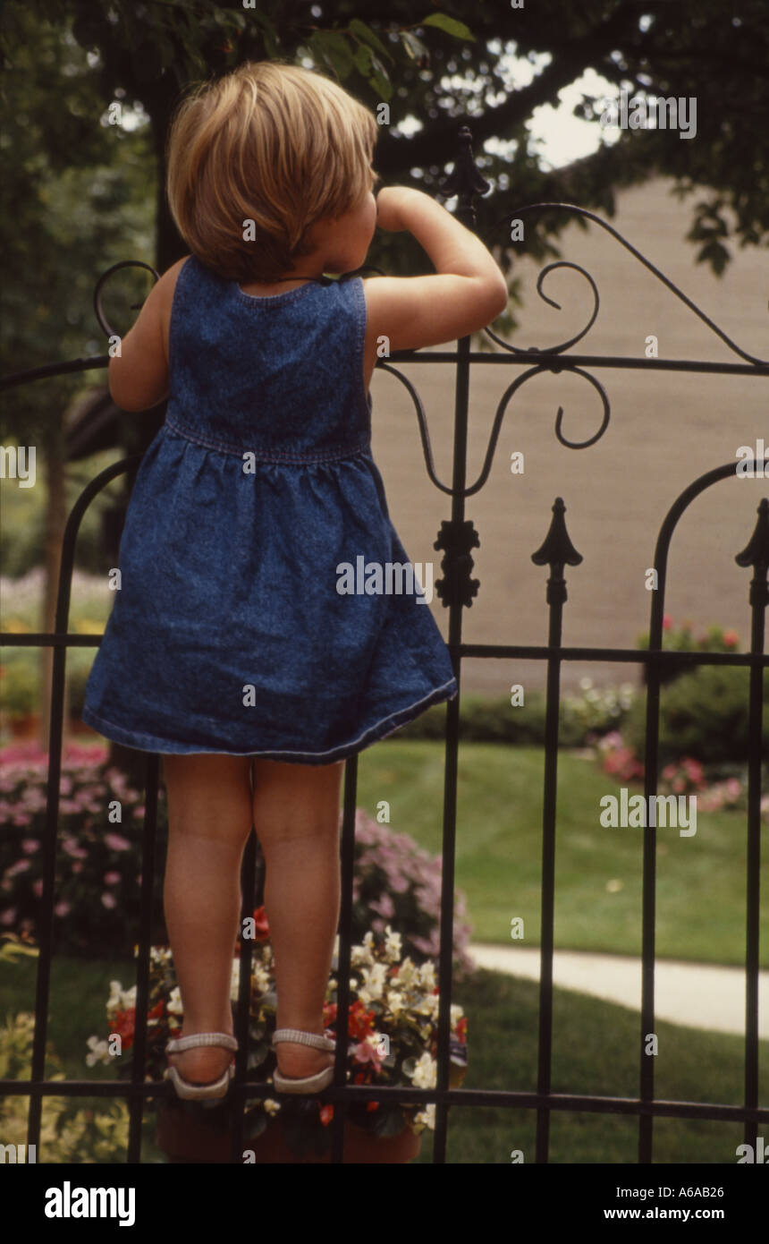 Girl looking through gate Stock Photo - Alamy