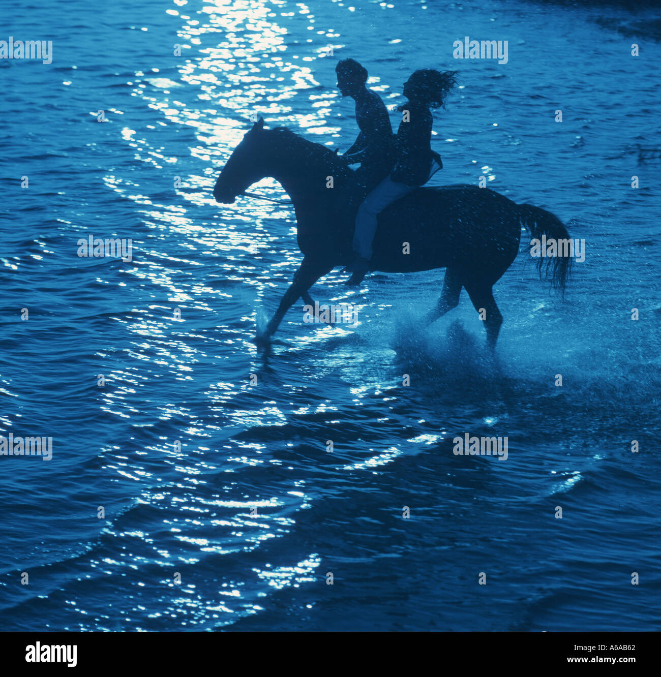 Couple riding horse in lake at night Stock Photo - Alamy