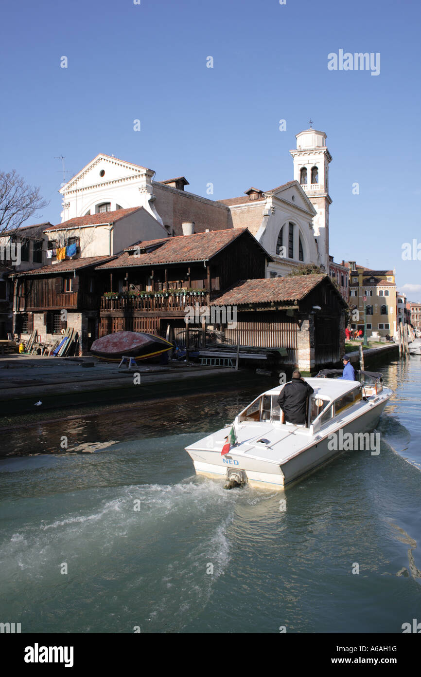 traditional shipyard for ships and gondolas with a passing motor boat ...