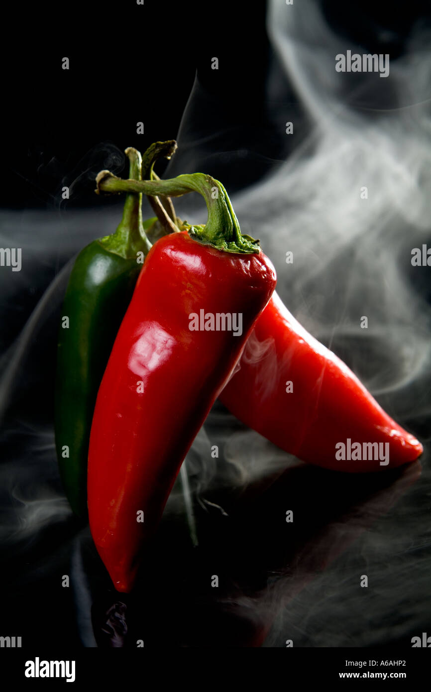 Red and green peppers on black reflective background with steam Stock ...