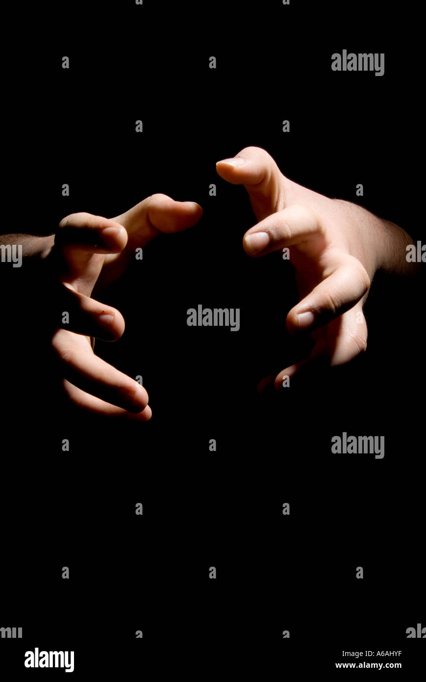 Grasping hands emerging from black background Stock Photo - Alamy
