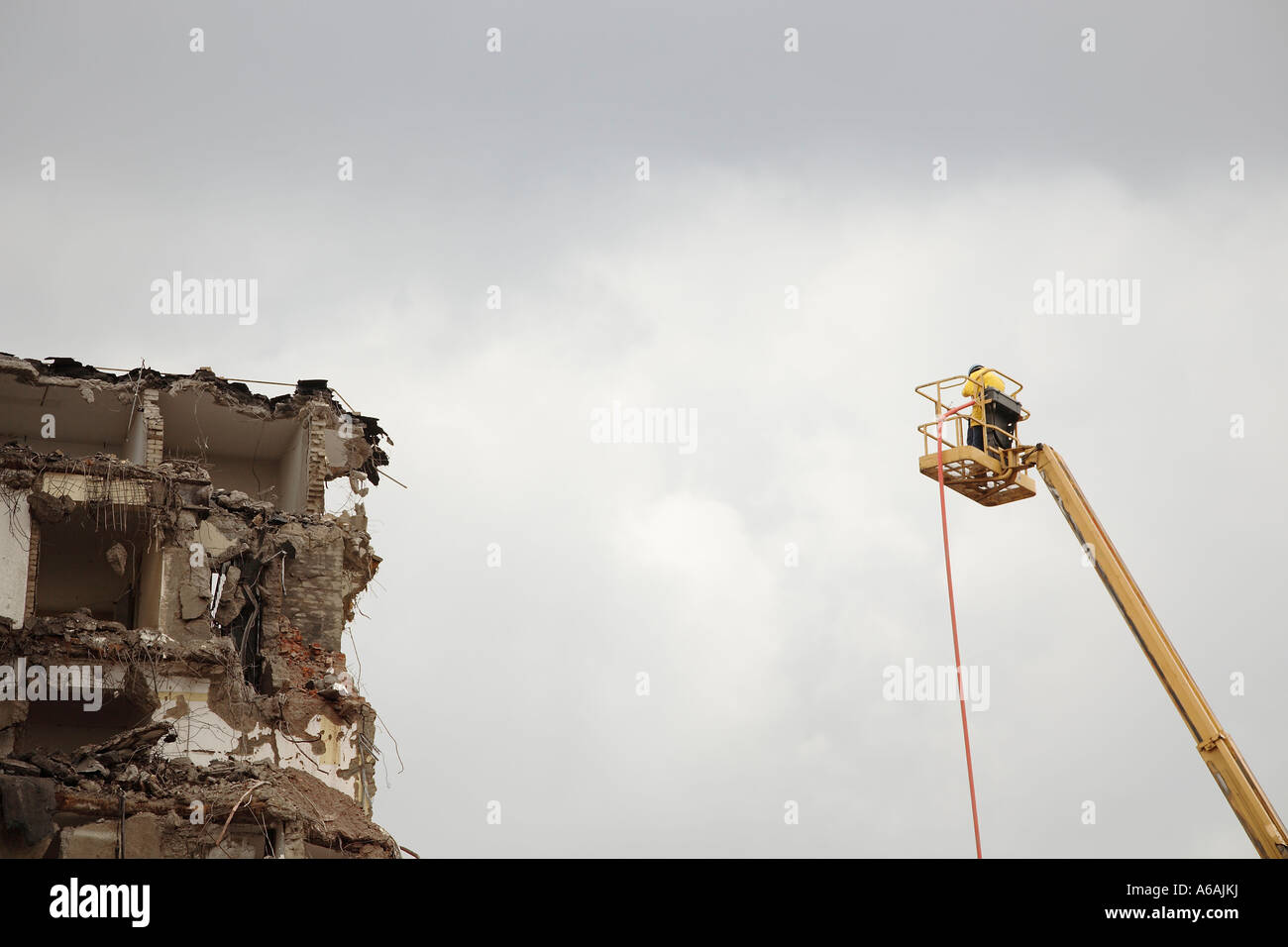 Building in the process of demolition with construction worker on crane ...
