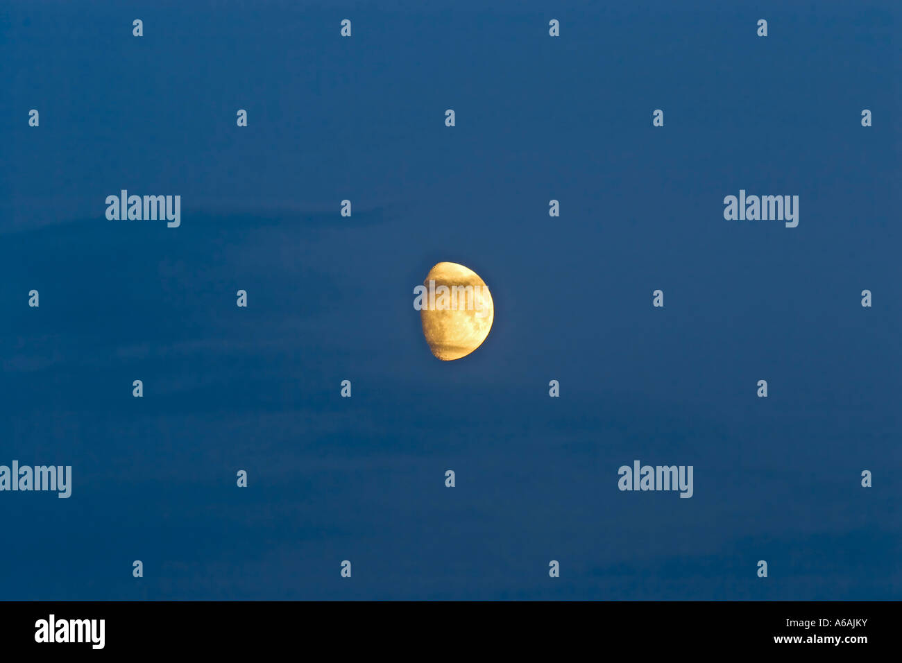 Yellow illuminated half moon against blue sky Stock Photo - Alamy
