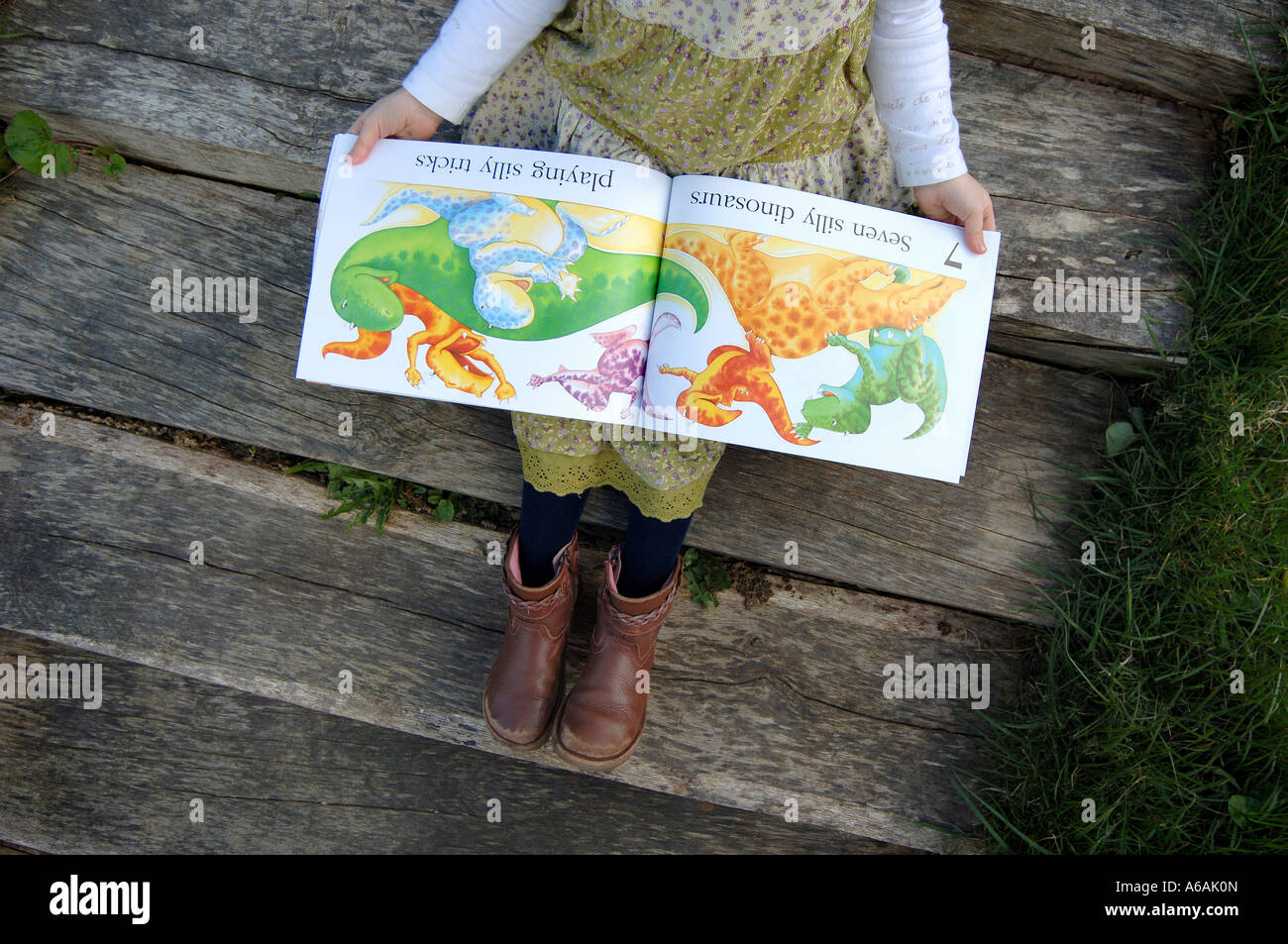 A child reading a maths book whilst sat on a step outdoors uk Stock ...