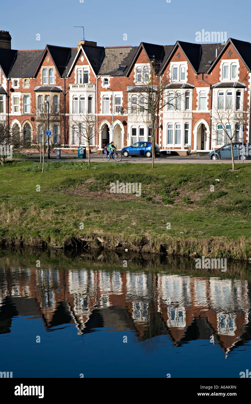 Person cycling past traditional terraced houses on the river Taff ...