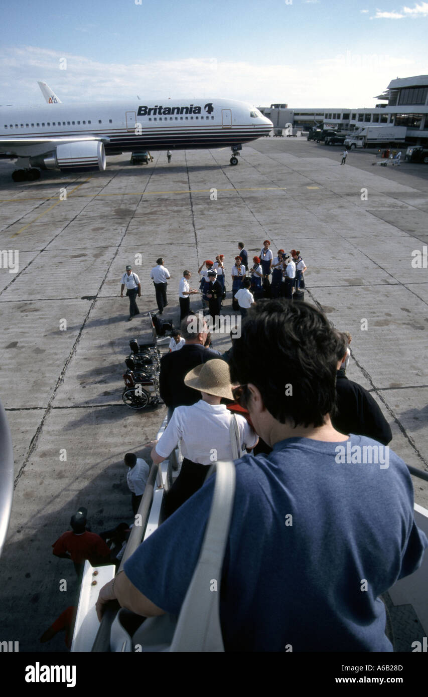 Plane passengers back view walk down air stairs leaving Britannia ...