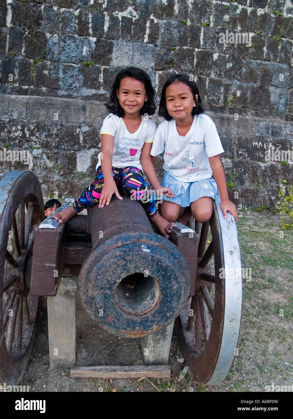 2 girls sitting on an old cannon outside of fort in Taytay Palawan ...
