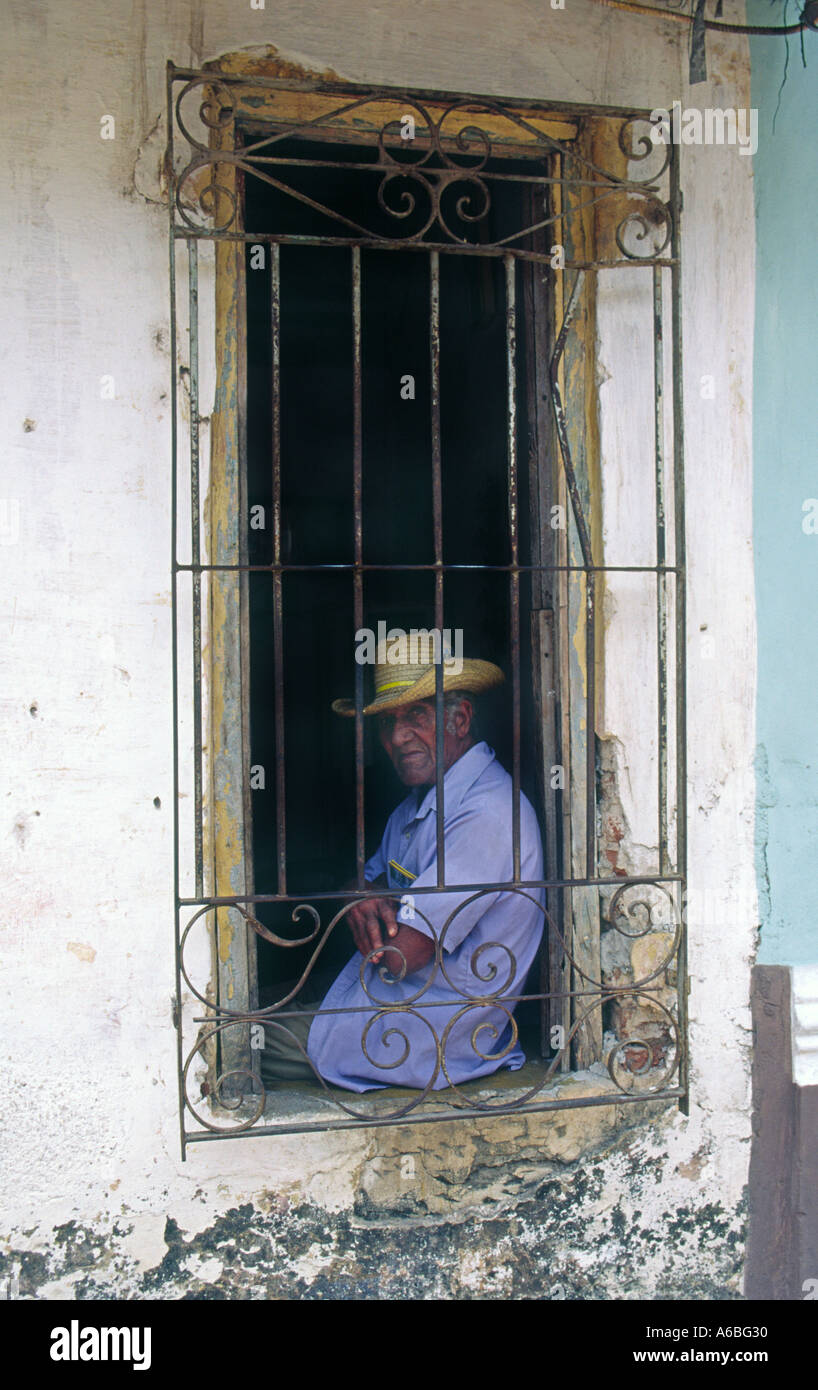 Man sitting on a window ledge in Trinidad Cuba Stock Photo - Alamy