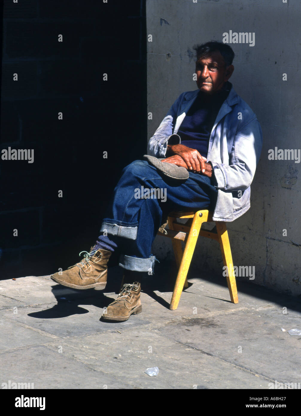 Local man resting on a chair in an alley in Whitby North Yorkshire ...