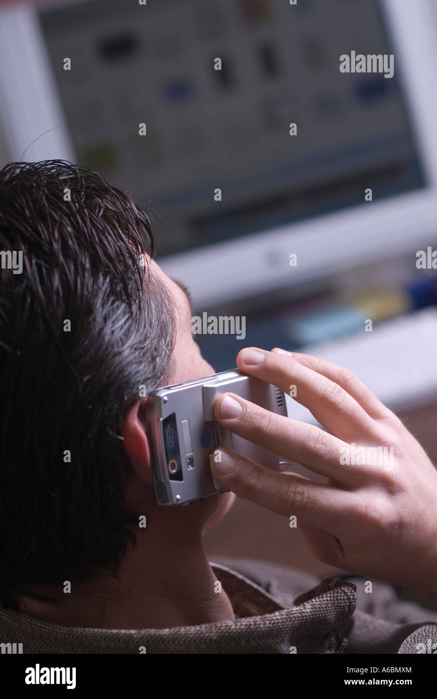 Businessman talking on a cell phone in front of a computer in an office ...