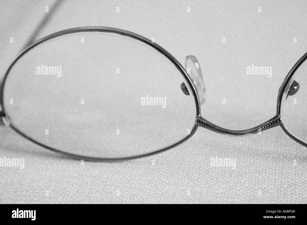 SPECS. Close-up of an upturned pair of glasses, showing the left lens ...