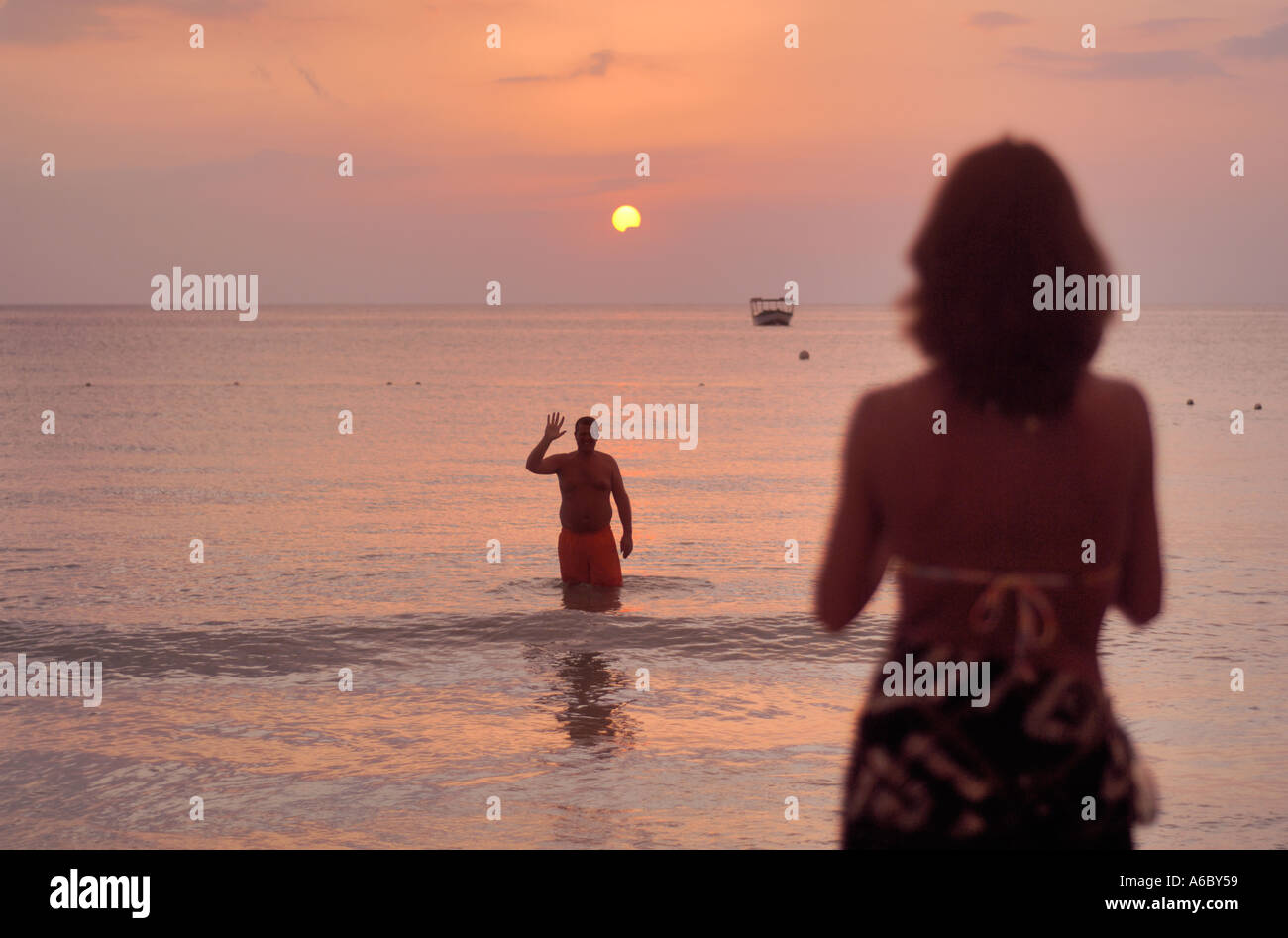 A color horizontal image of a paunchy middle aged man in swim trunks in ...