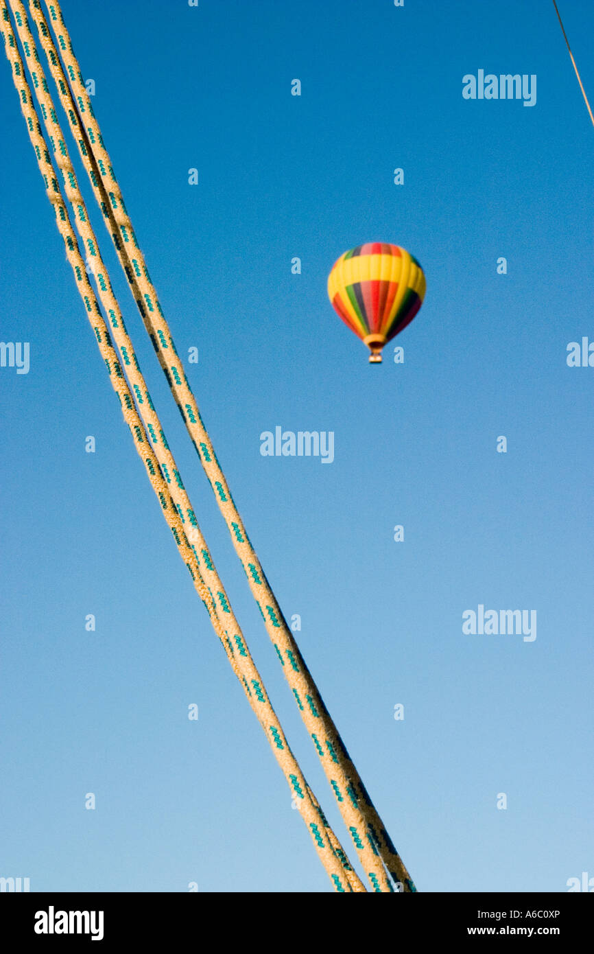 A single hot air balloon seen against a vivid blue sky, with ropes from ...