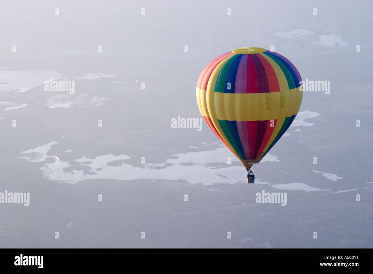 A single colorful hot air balloon floats over a misty landscape with ...