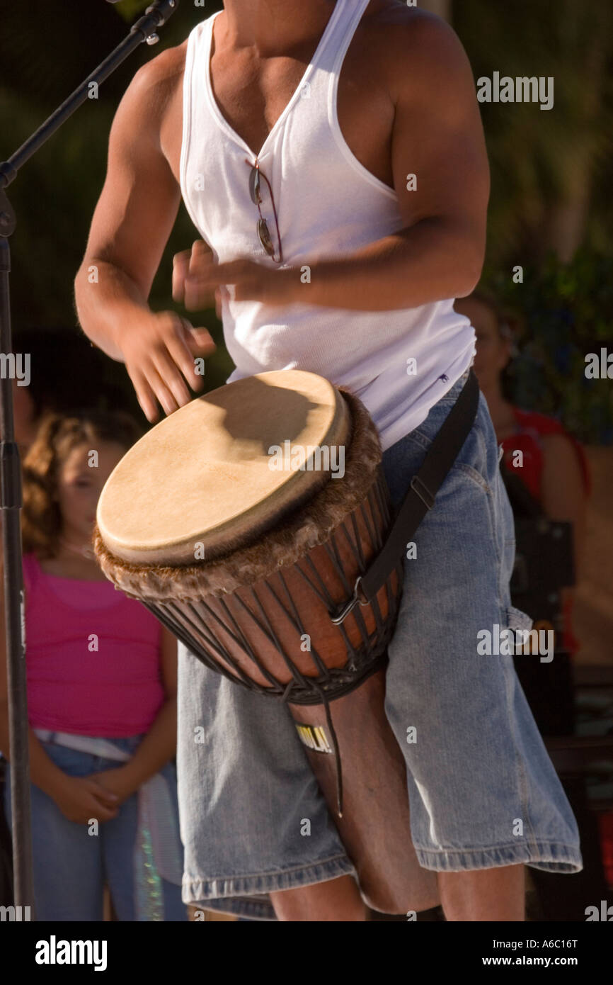 A hip young black man plays a bongo drum at an outdoor music festival ...