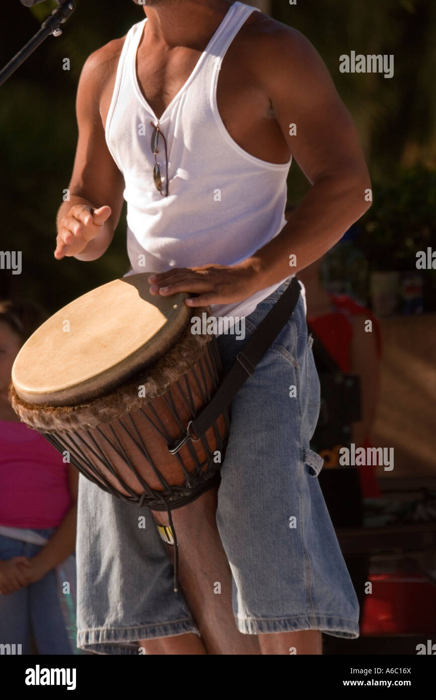 A hip young black man plays a bongo drum at an outdoor music festival ...