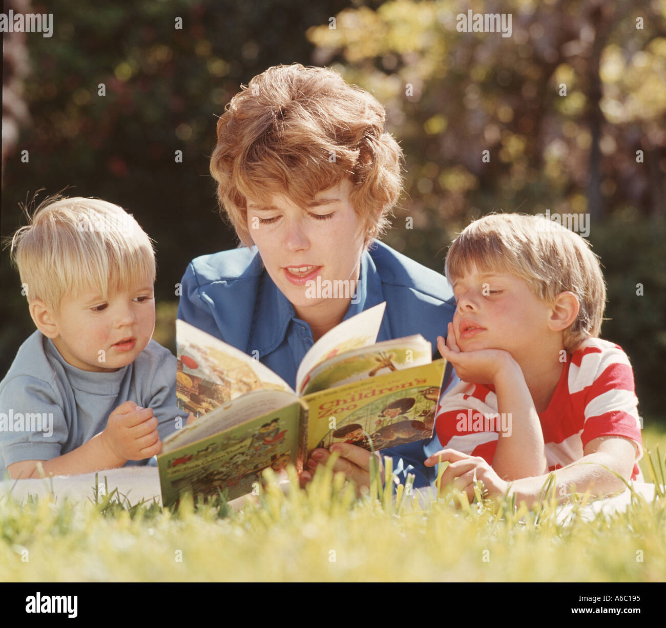 mother reading book to two sons on lawn Stock Photo - Alamy