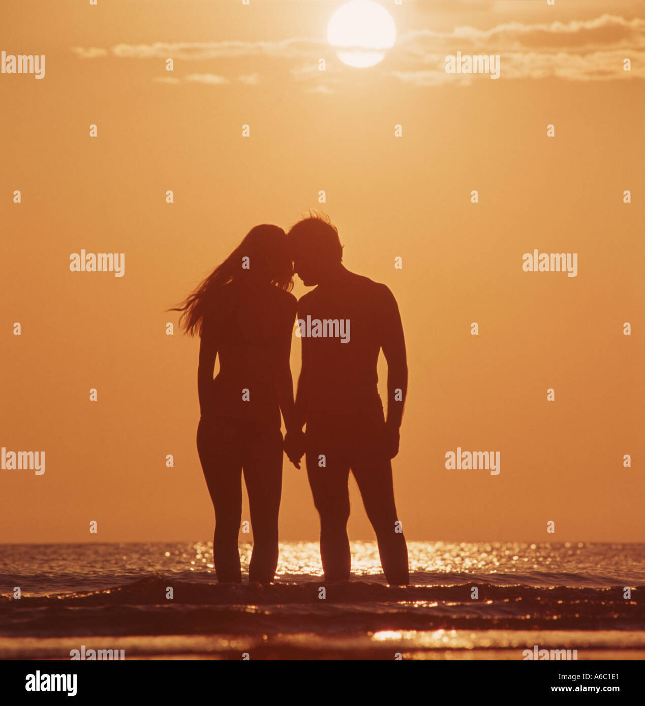 romantic couple wading in surf at sunset Stock Photo - Alamy