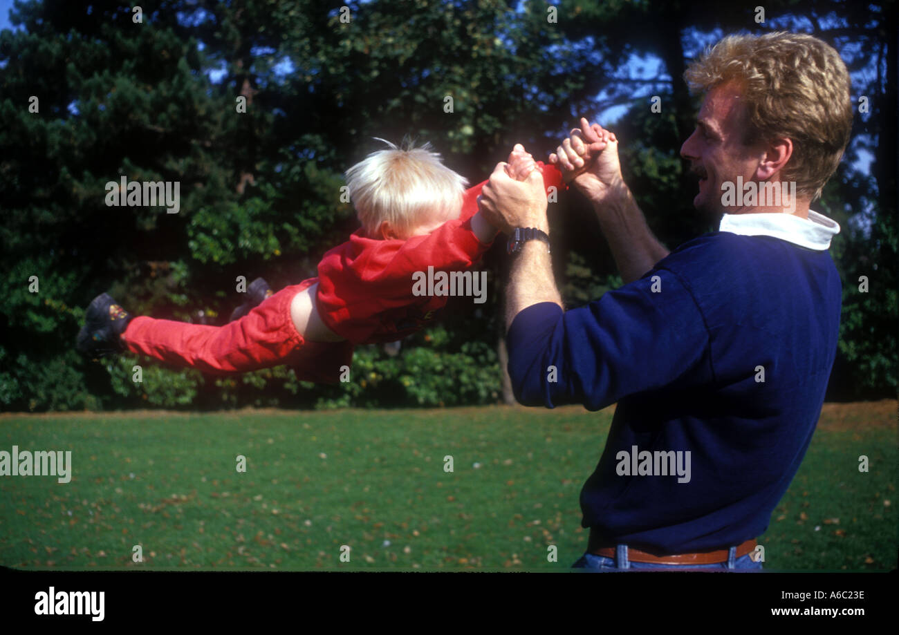 Young boy being spun around in the air by arms by father in the park ...