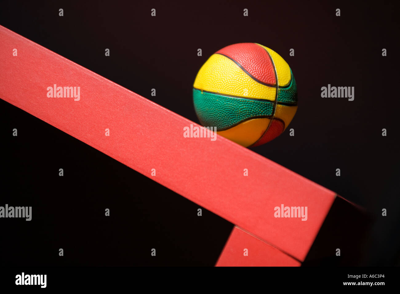 Colorful ball on red table sliding down Stock Photo - Alamy