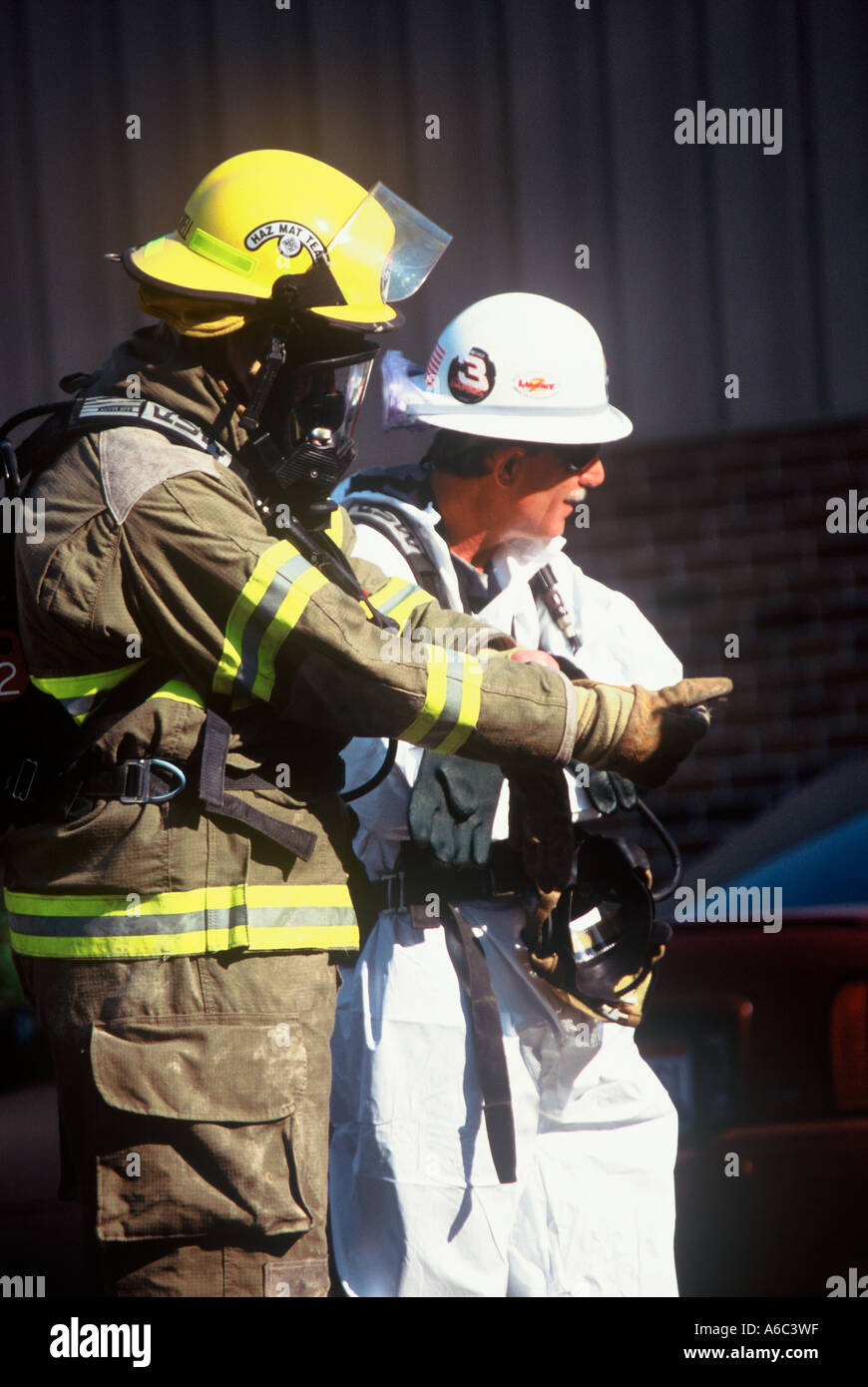 A fire fighter is talking to a hazmat specialist at a scene of a ...