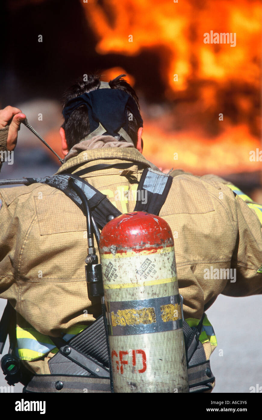A fire fighter is putting on gear and getting ready to put out a fire ...
