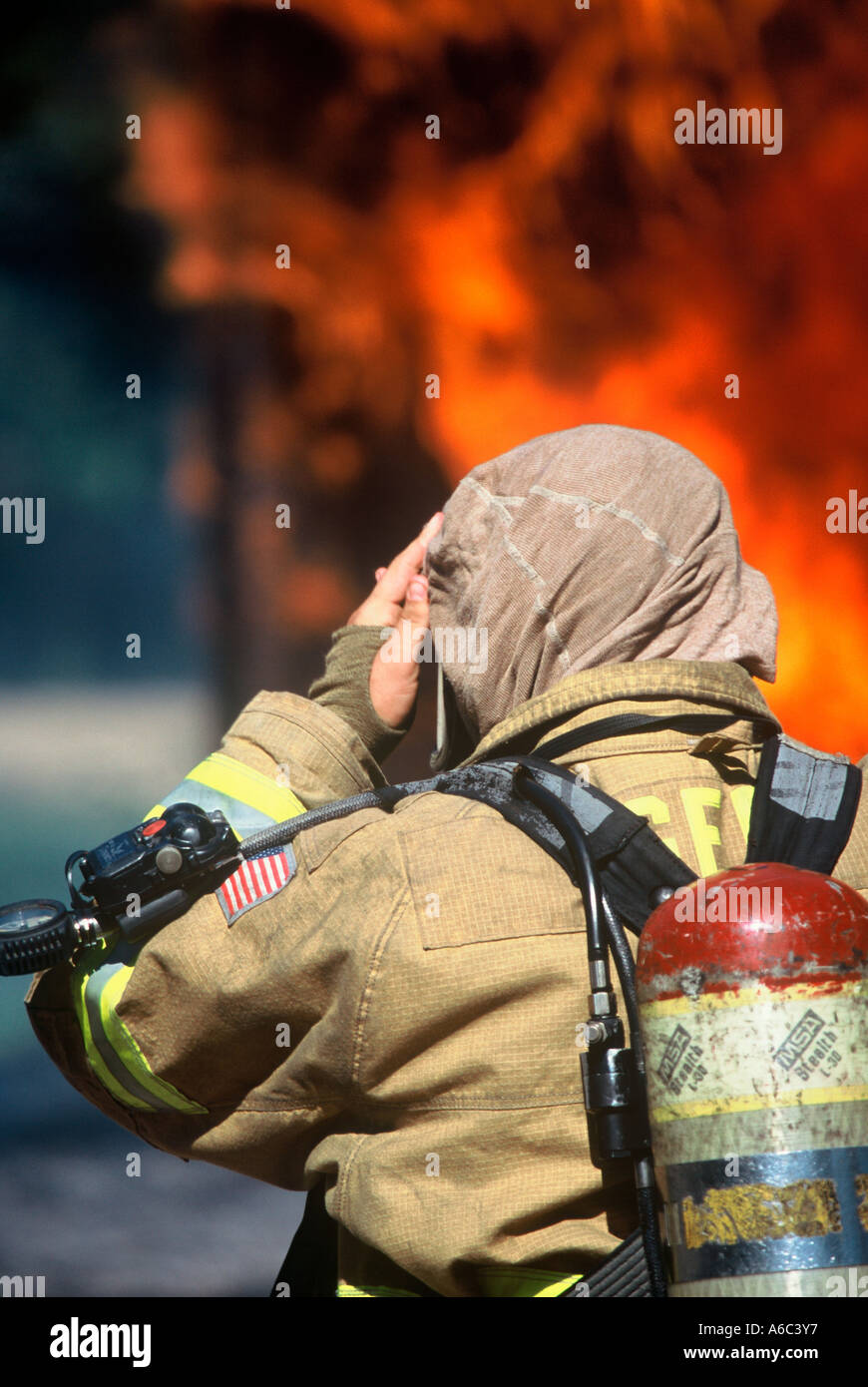 A fire fighter is putting on gear and getting ready to put out a fire ...