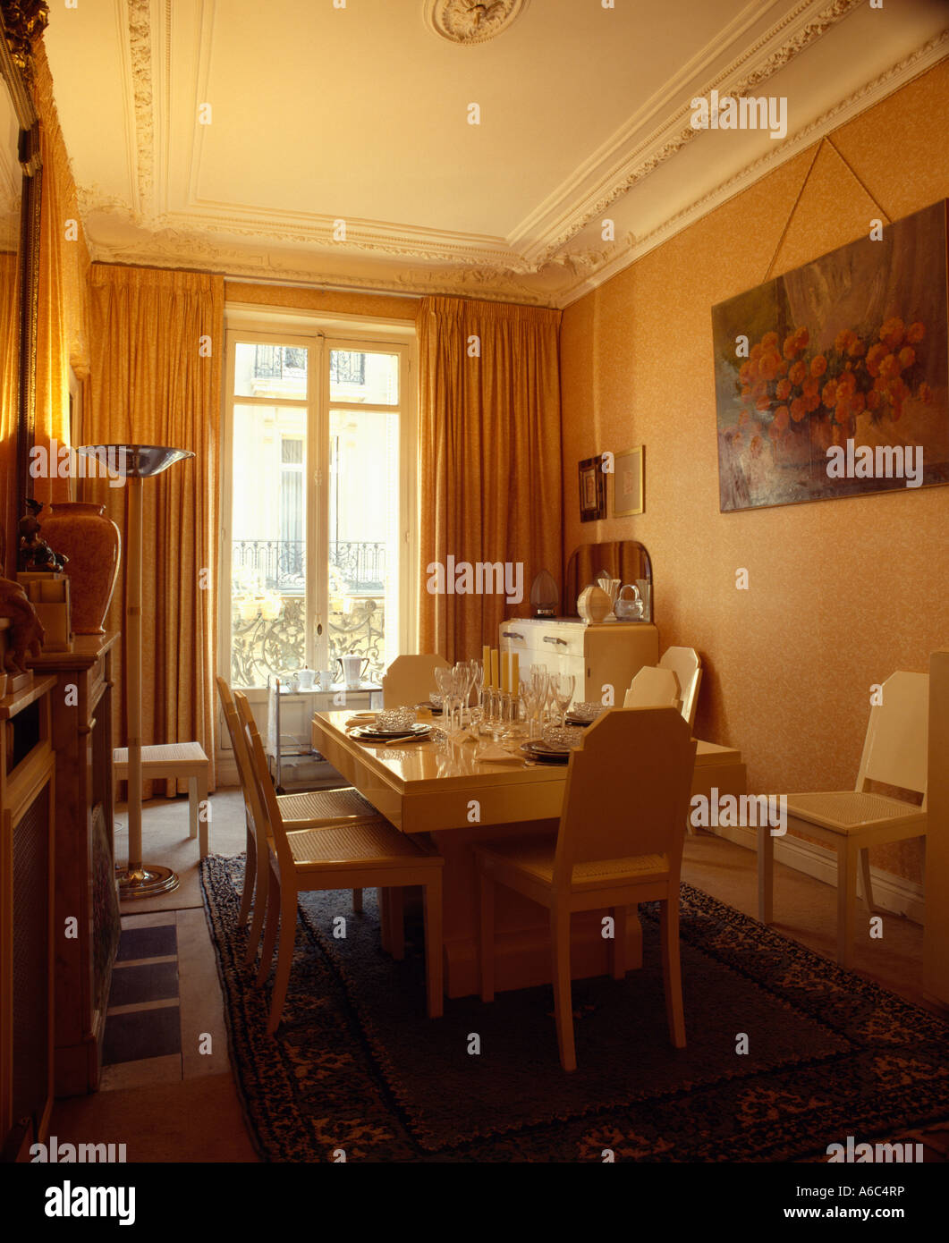 White table and chairs in pastel orange diningroom with ornate cornice ...