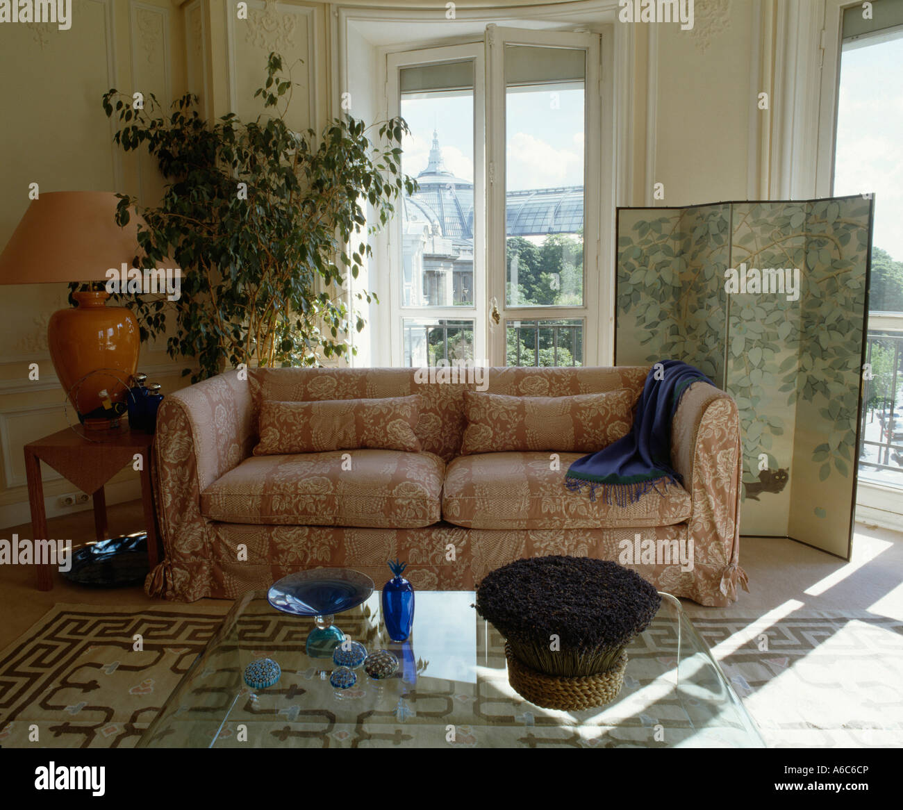 Pink sofa in front of French windows and folding screen in Paris ...