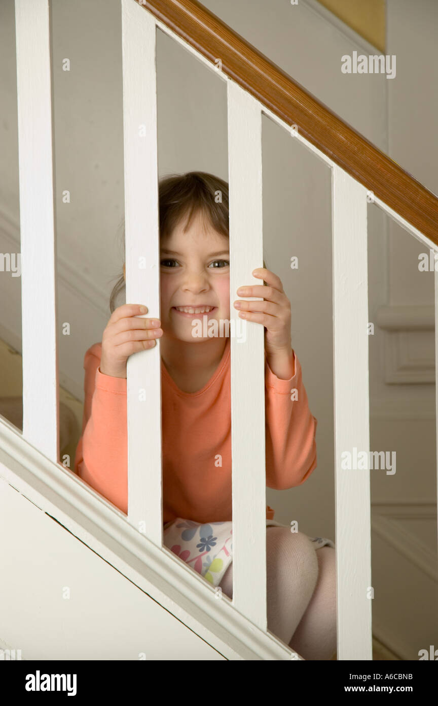 Young child looking through pickets on a staircase railing Stock Photo ...