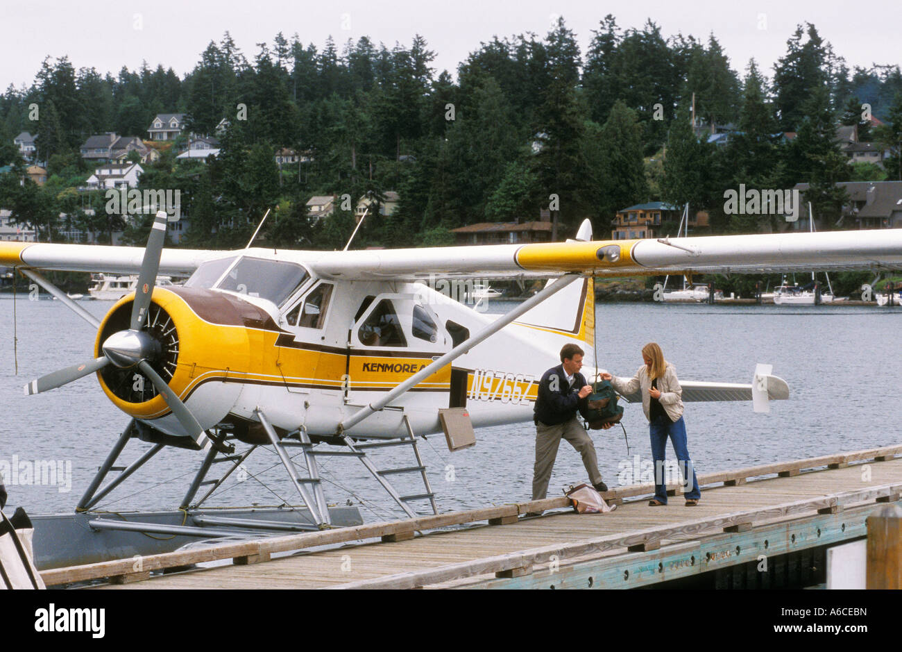 Kenmore Air seaplane at dock and pilot helping passenger with baggage ...
