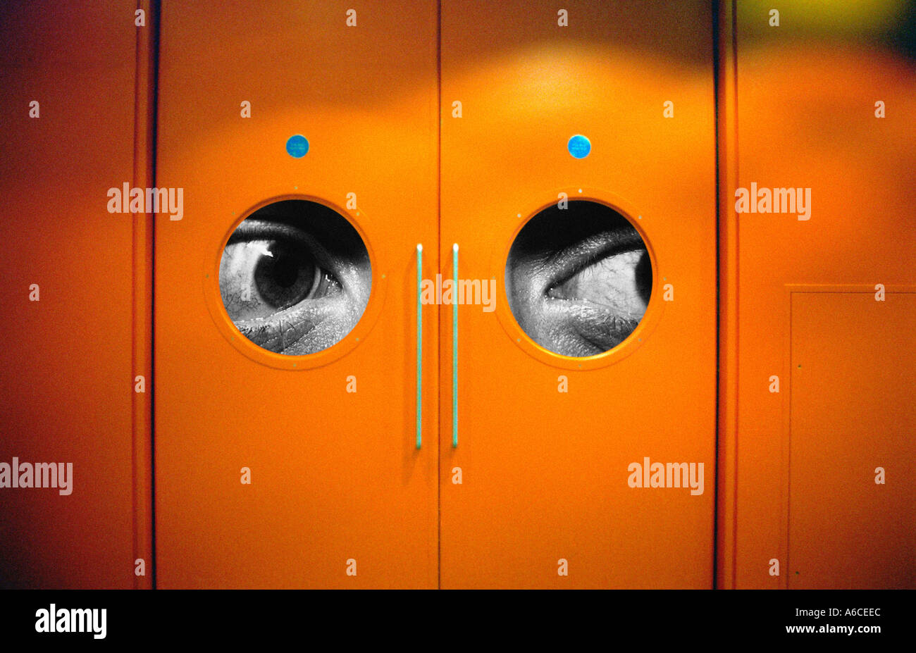 Eyes peering through door portholes in office Stock Photo - Alamy