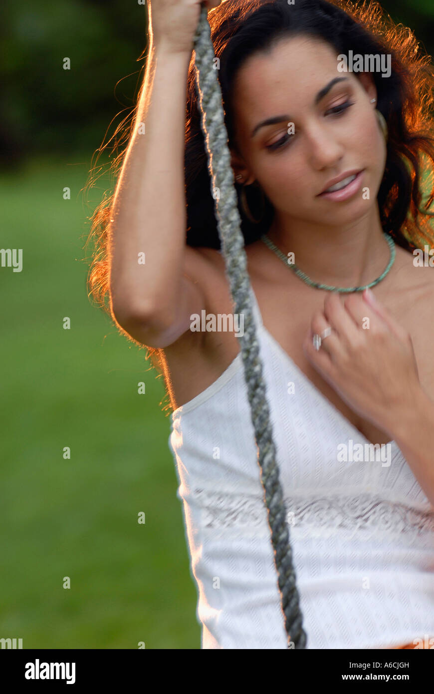 Close-up of a young woman sitting on a rope swing Stock Photo - Alamy