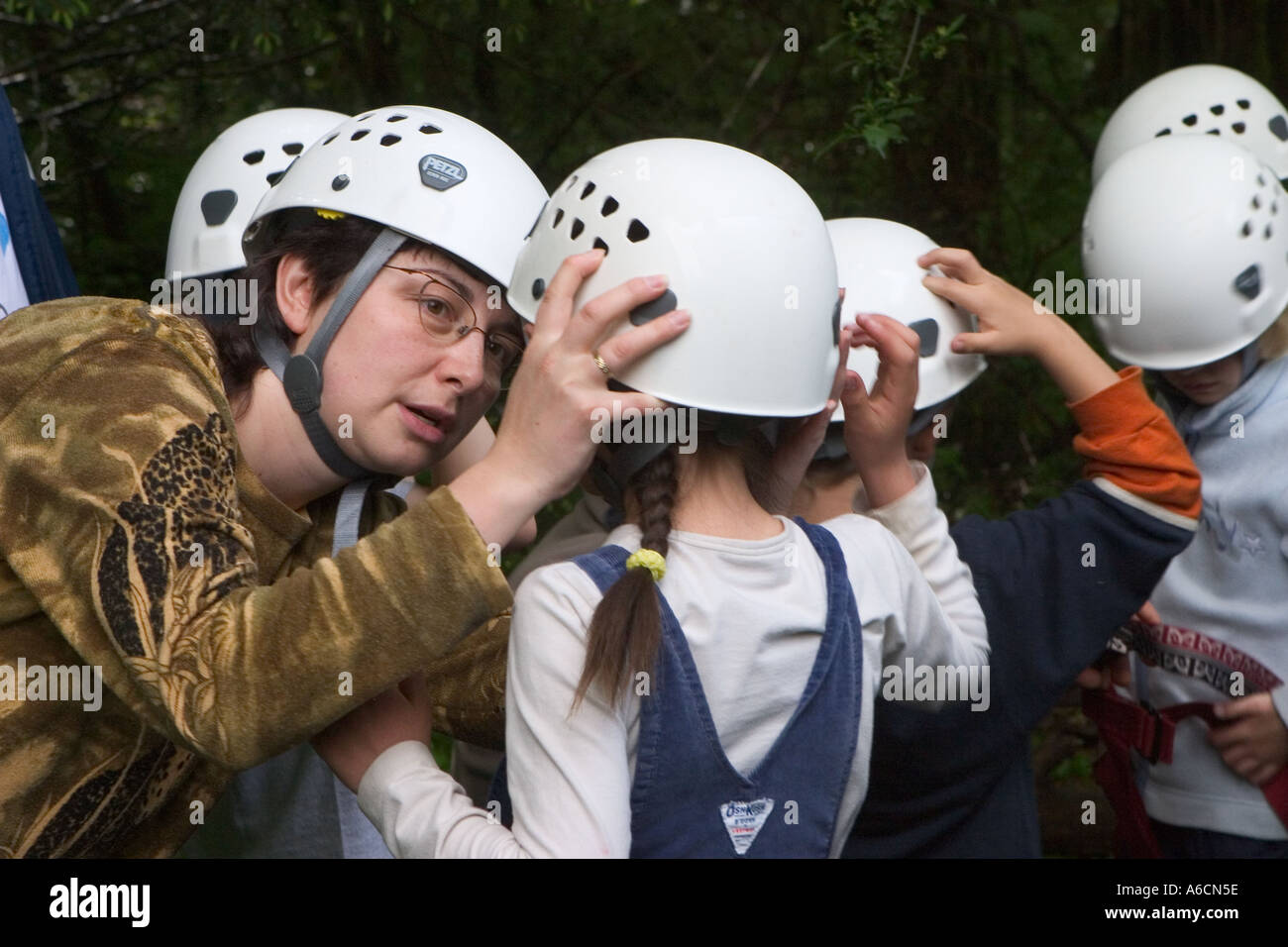 Young children prepare for a tree climbing exercise at an outdoor event ...