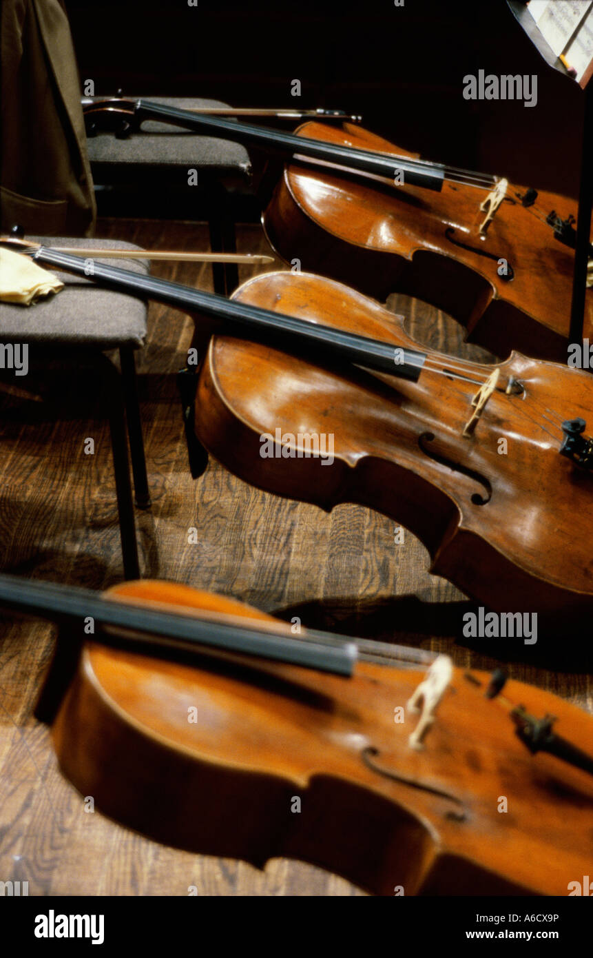 Three violins resting against chairs Stock Photo - Alamy