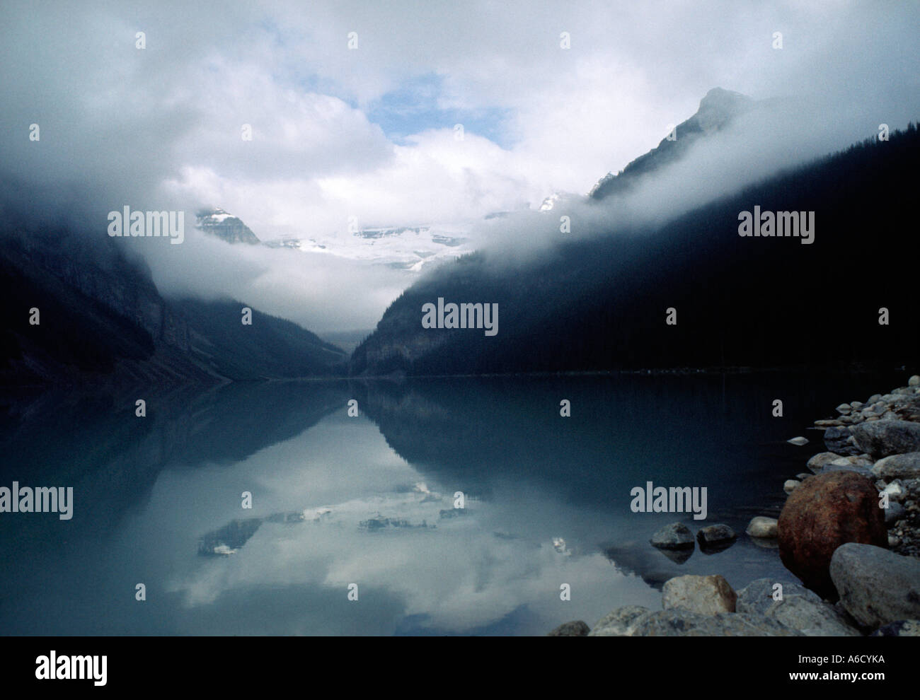 FOG and MOUNTAIN PEAKS reflected in LAKE LOUISE ALBERTA CANADA Stock ...