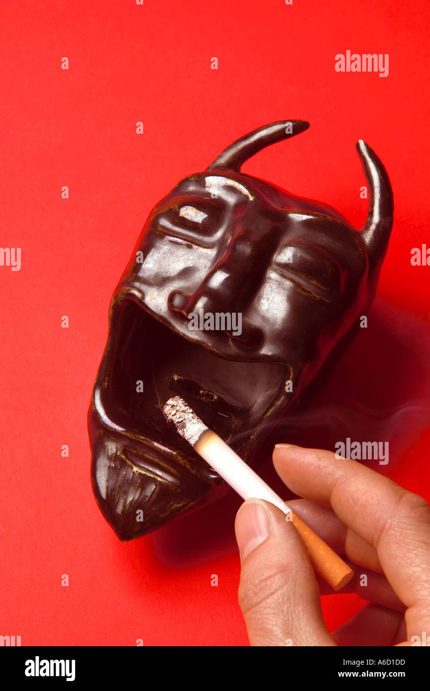 Person knock off ash from cigarette in devil ashtray Stock Photo - Alamy
