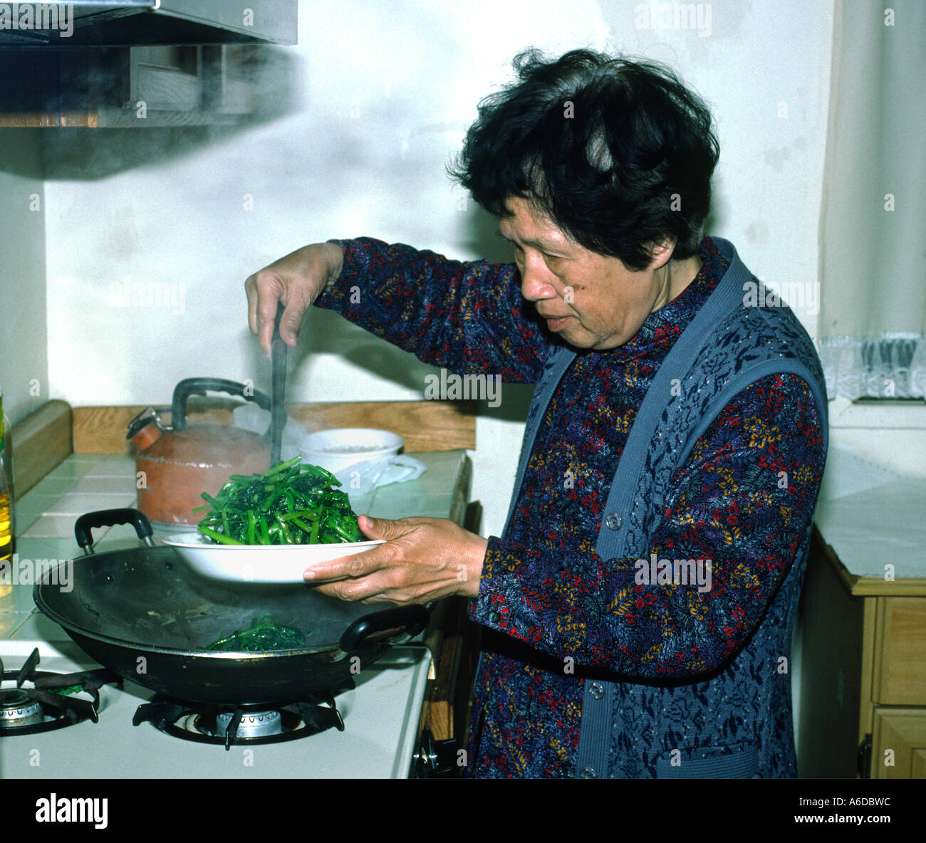 24893 elderly Chinese woman cooking vegetables in wok on stove Stock ...