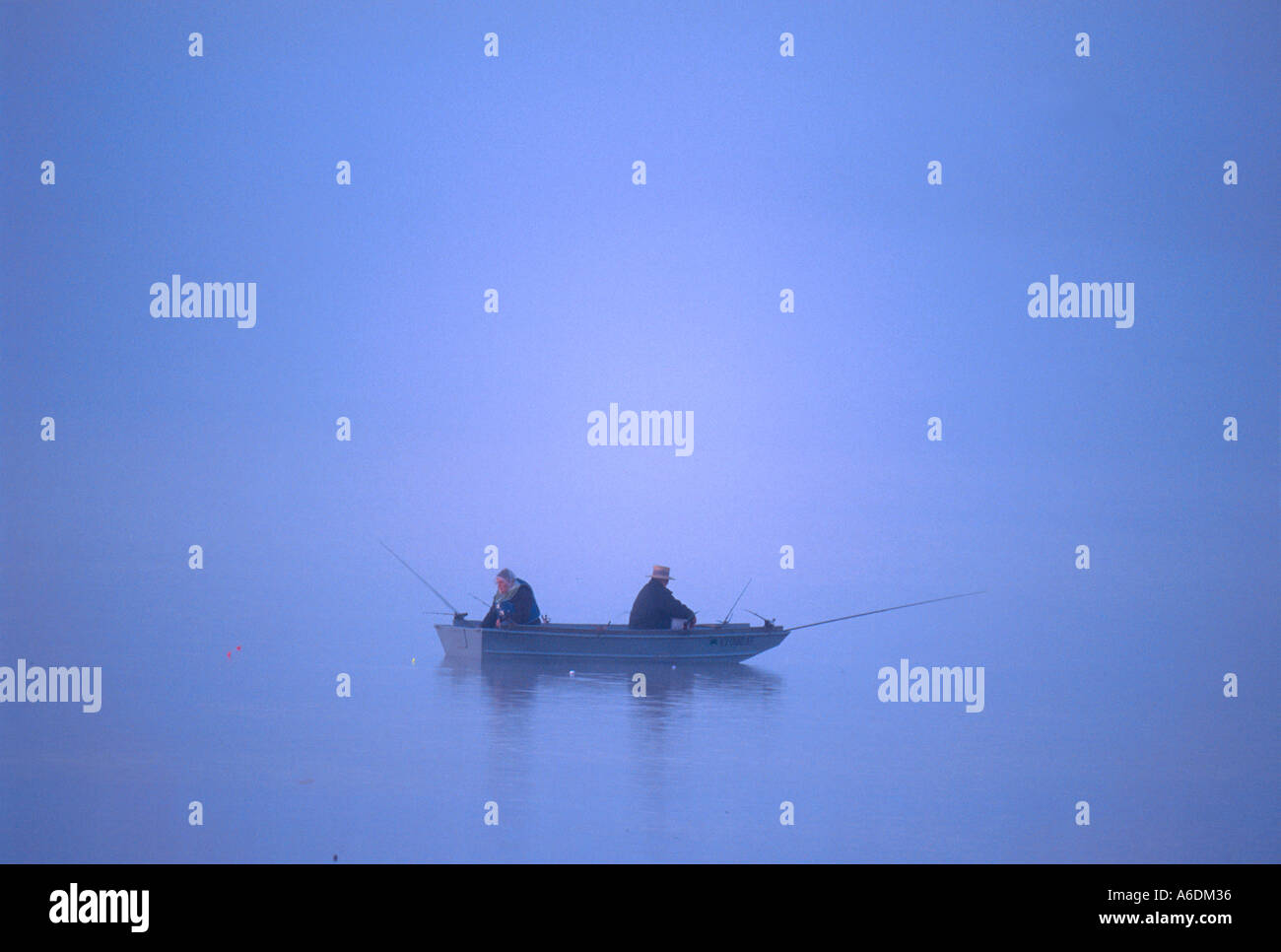 Old couple sitting back to back in a small rowboat while fishing in ...