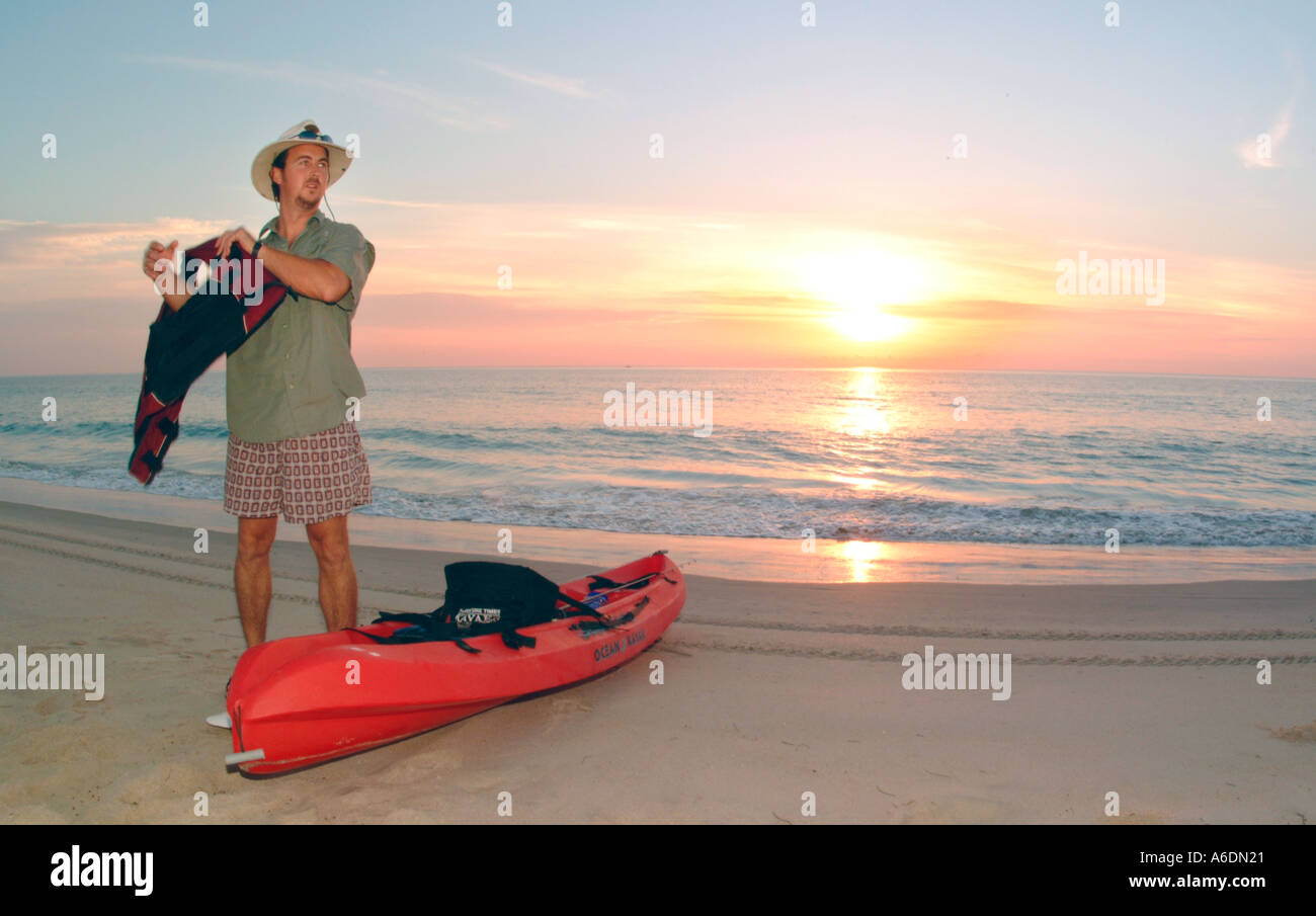 man putting on life jacket vest preparing to go fishing from a kayak ...