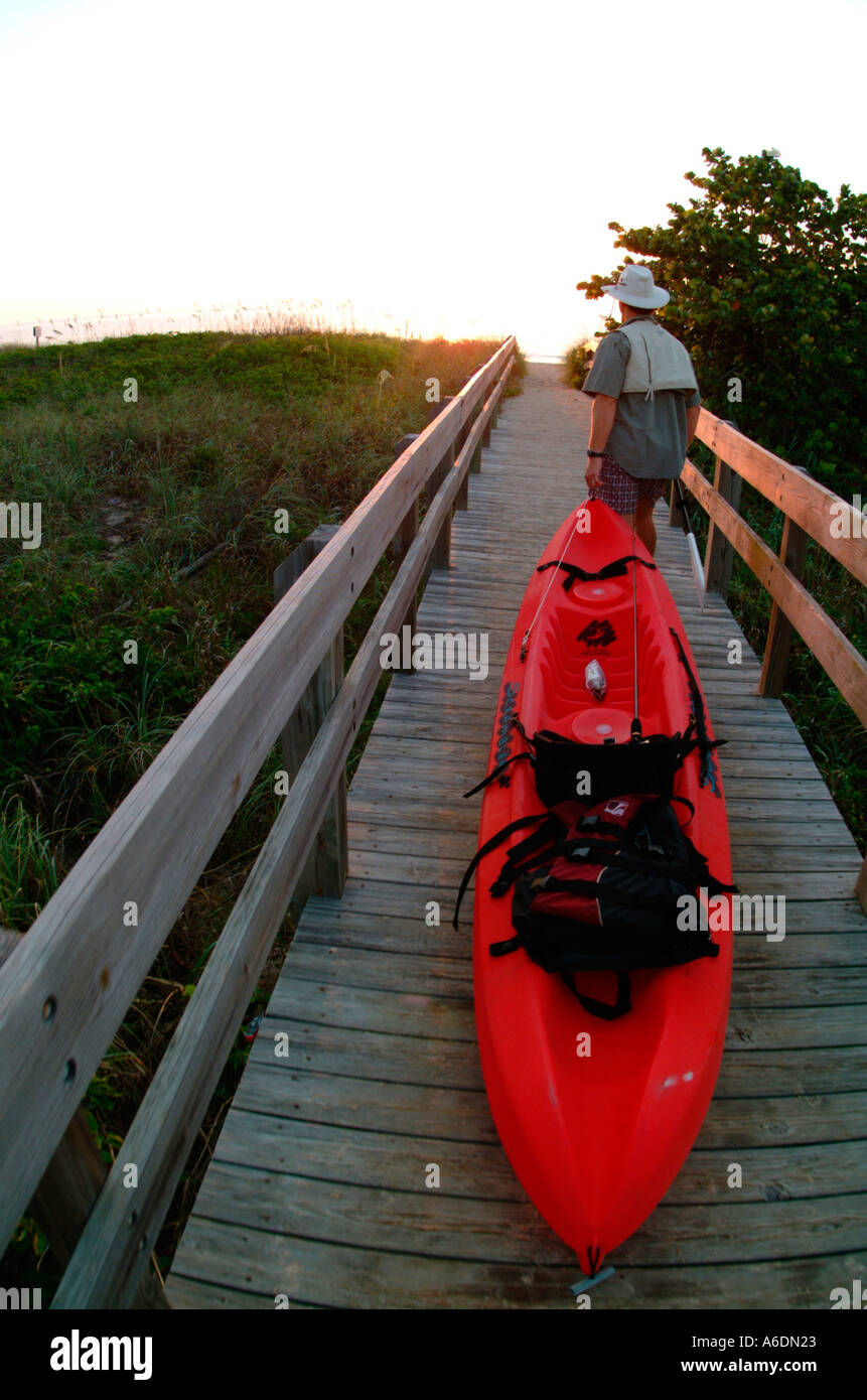 man walking down boardwalk preparing to go fishing from a kayak off ...