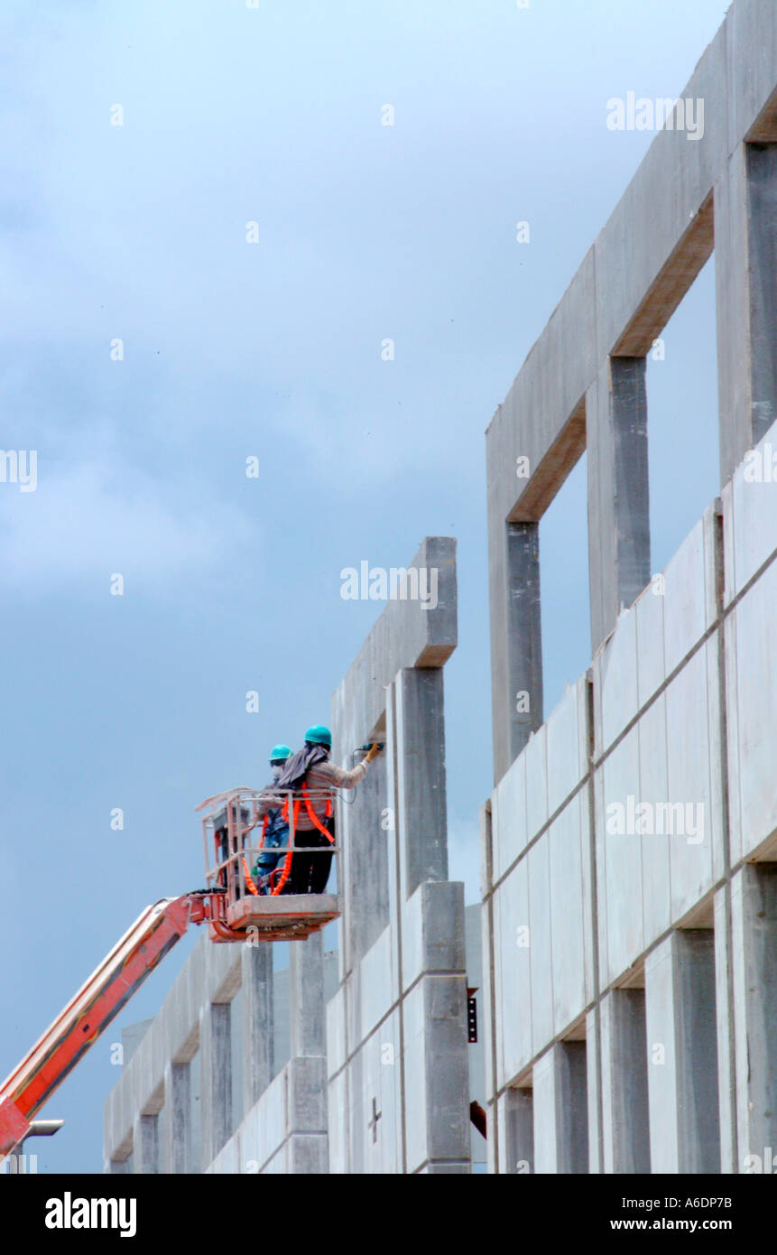 Construction workers grinding a pre formed cement wall of a building ...