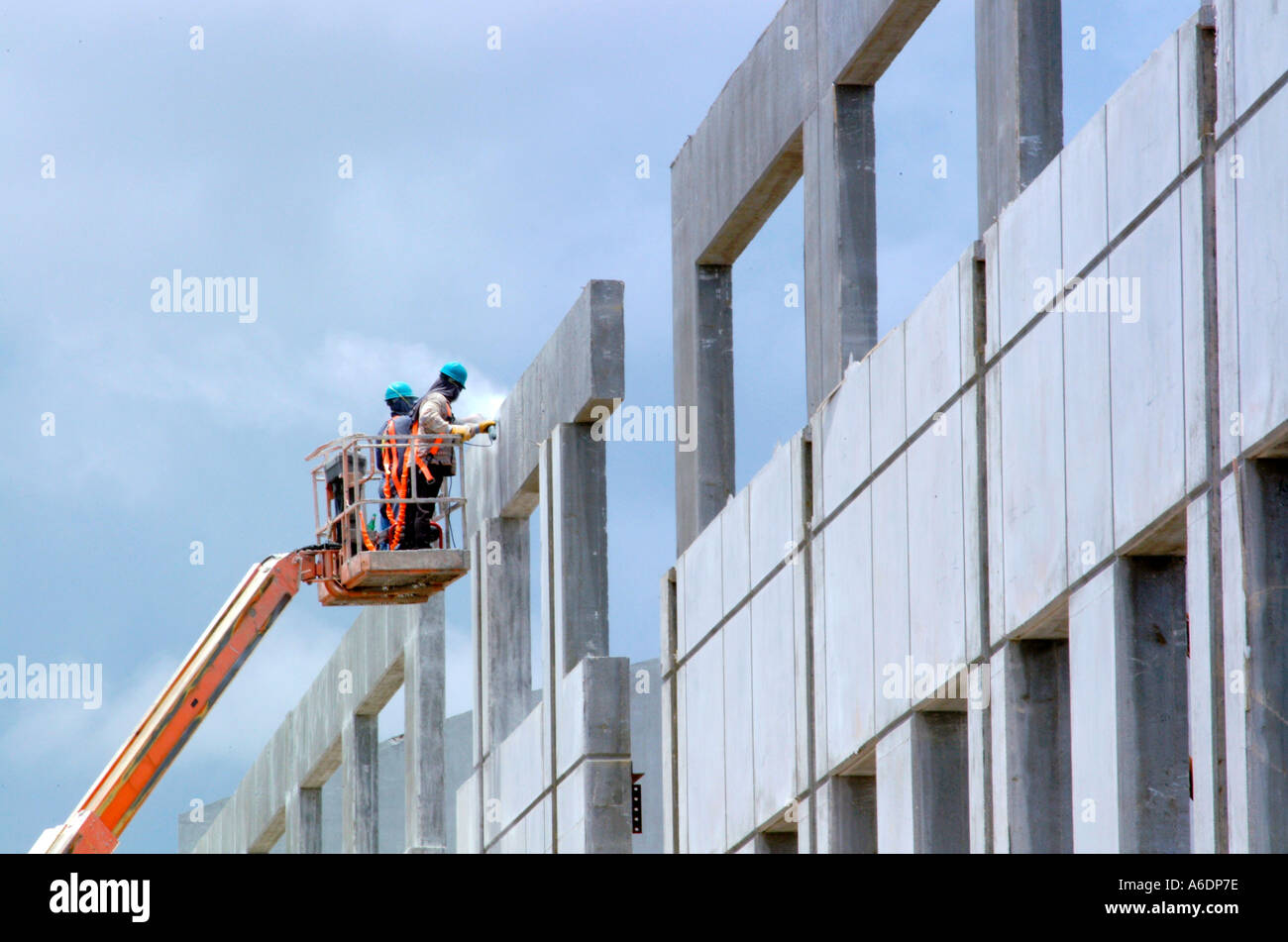 Construction workers grinding a pre formed cement wall of a building ...