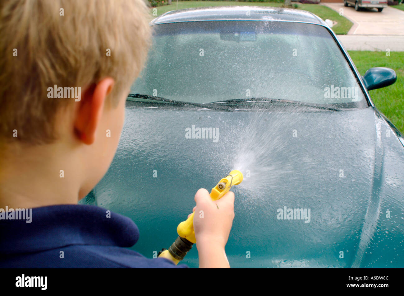 boy washing car spraying automobile with hose vehicle water cleaning ...