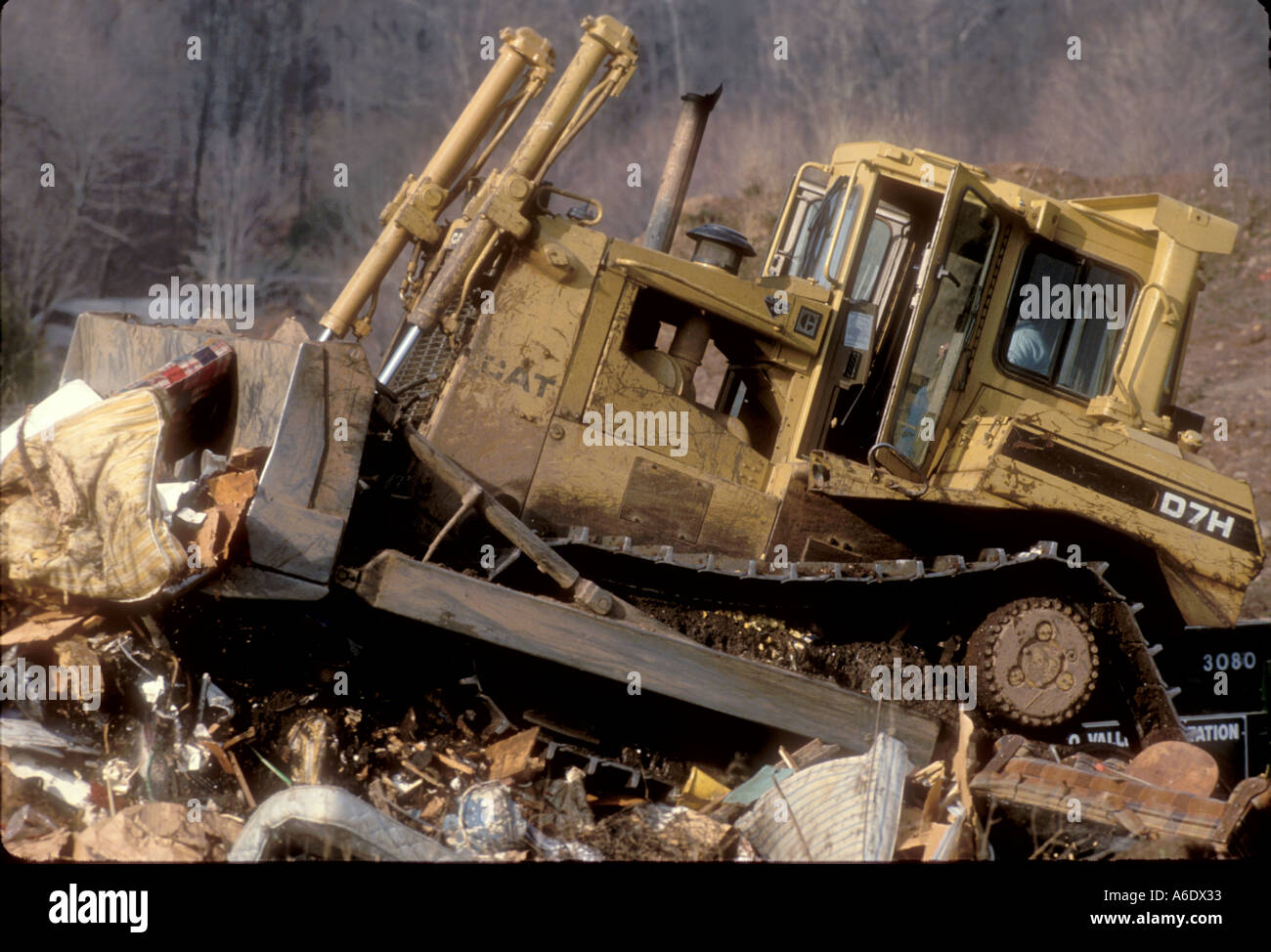 bulldozer driving over garbage to pack it down in landfill dump heavy ...