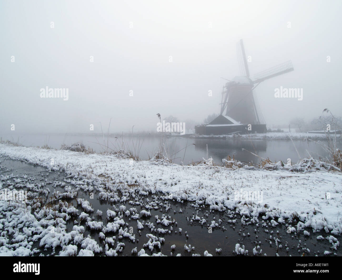 Dutch winter landscape with fog and windmill silhouette Kinderdijk the ...