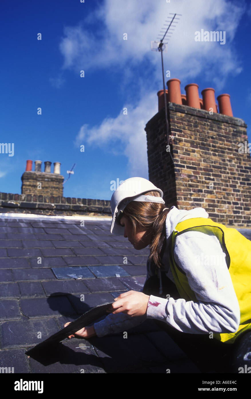 Female construction worker fixing slates on roof top Stock Photo - Alamy
