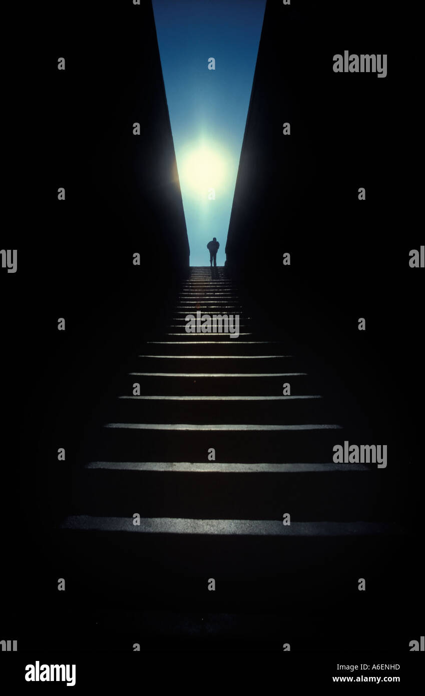 A lone figure emerging from a long narrow stone stairway is silhouetted ...